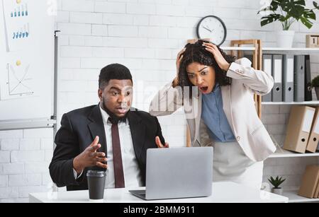 Anxious African American colleagues finding mistake in project or ...