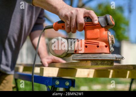 Unrecognizable man in the garden sanding wooden planks. DIY home ...