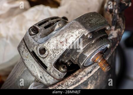 An old angle grinder in bucket. A damaged electrical hand tool ready ...