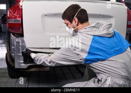 Mechanic covering car with duck tape before painting in auto repair ...