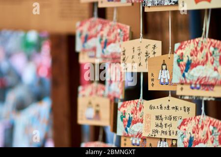 Wooden cards (ema) with prayers and wishes and white paper omikuji ...