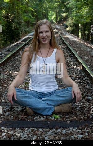 Pretty Blond sitting on Railroad Tracks with a smile Stock Photo - Alamy
