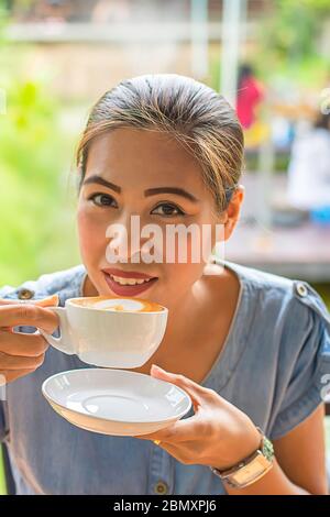 Portrait of an Asian business woman drinking coffee while reading book ...