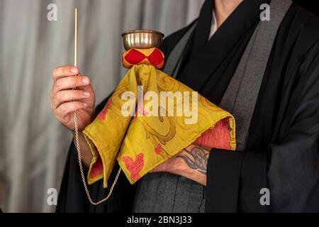 Zen monk sounding a hand-bell called inkin during a buddhist ceremony ...
