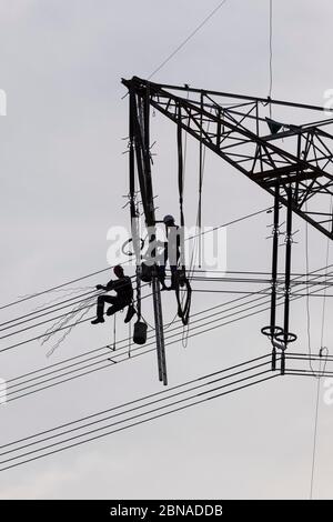 Silhouette of an industrial rope access worker cleaning or maintaining ...