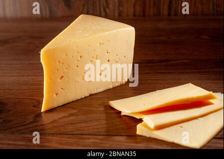 ordinary cheese on a wooden background sliced with slices lies on the ...