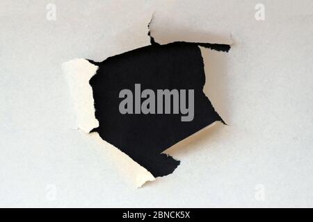 Breakthrough paper hole with black textured background Stock Photo - Alamy