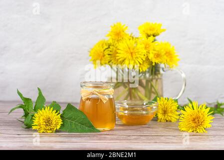 Dandelion jam or honey in the glass jar with a bouquet of fresh ...