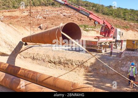 Workers are laying metal culverts under the highway under construction ...