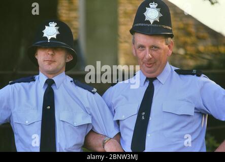 Two male police constables posing for a laugh with the wrong size ...