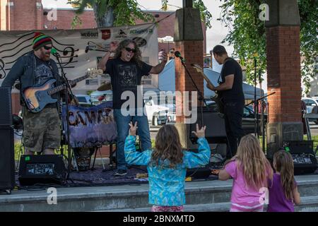 Rock band performing outdoorss, with yong kids dancing to the music ...