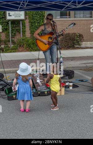 Pretty, blonde, female folk singer, playing guitar and singing at ...