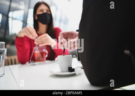 couple with protective medical mask having coffee break in a restaurant ...