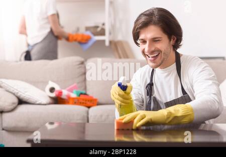 Smiling man wiping dust from a chair in room Stock Photo - Alamy