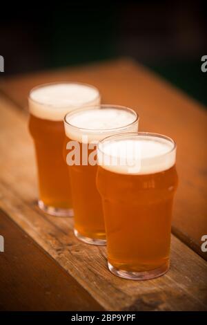 Three pints of beer in a row, on a table Stock Photo - Alamy