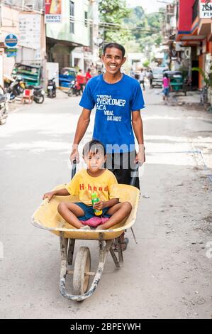 A cute little filipino boy gets a lift in a wheelbarrow along the ...