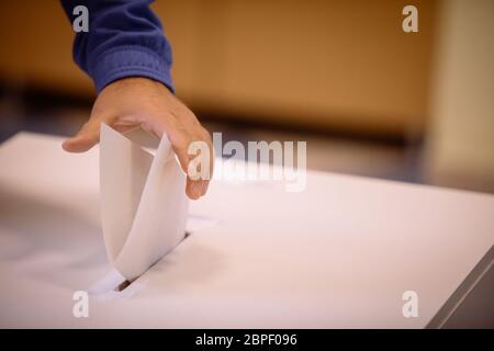 Color image of a person casting a ballot at a polling station, during ...
