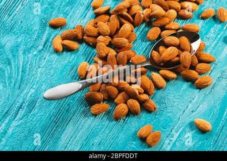 handful of almonds in metal spoon on a blue wooden background Stock ...