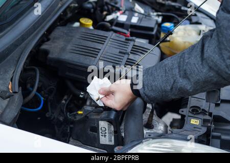 Man checks with oil dipstick and paper towel,the engine oil level of a ...