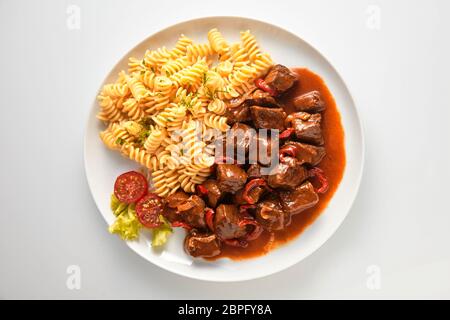 Wild deer venison goulash with fusilli pasta served on a white plate ...