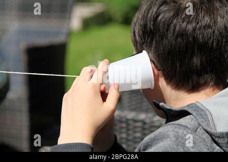 Using a telephone made from plastic cups and string, science experiment ...