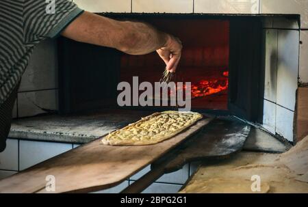 Turkish Muslim baker man pouring sesame over traditional ramadan bread ...