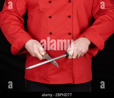 chef in black uniform and red apron holds a round pan with fresh chili ...