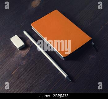 Orange notepad, pencil and eraser on wooden table Stock Photo - Alamy