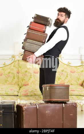 Macho, elegant porter on strict face carries pile of vintage suitcases ...