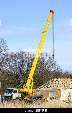 Mobile truck-mounted crane lifting heavy concrete building materials on ...