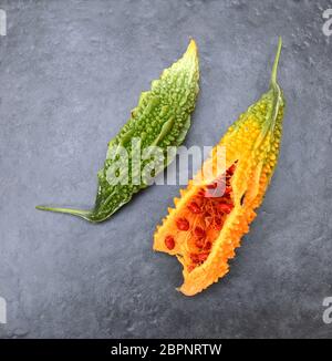 Orange, overripe bitter gourd split open with red, sticky seeds and a ...