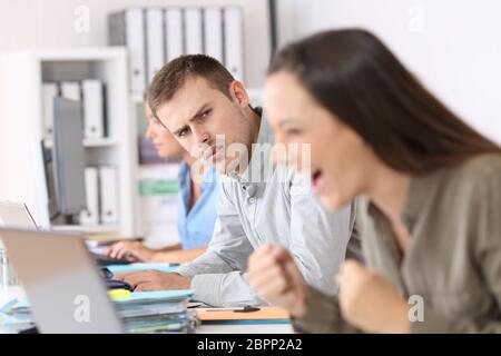 Portrait of a jealous employee looking at a successful colleague at ...