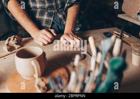 Male potter rolls clay to create a cup Stock Photo - Alamy