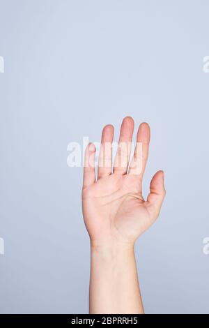 Female hand raised with an open palm, symbolizing greeting, waving, or ...