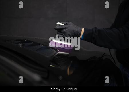 The master polishes the car. Vehicle detailing. A young man polishing ...