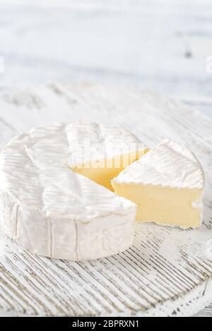 sliced round brie cheese head with white mold on white paper Stock ...
