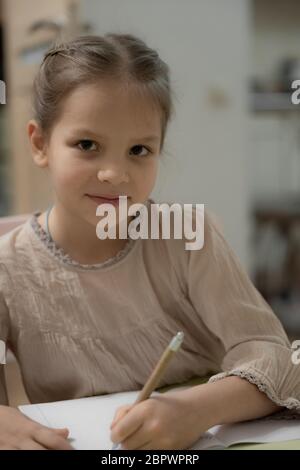 A dark blond girl in a beige dress is doing homework Stock Photo - Alamy