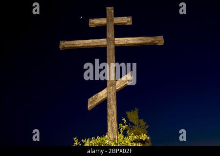 Huge wooden Orthodox eight-pointed cross against the sky after sunset ...
