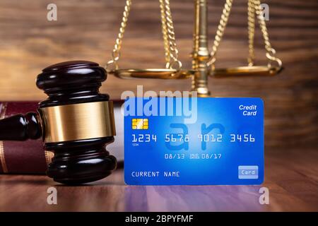 Blue Credit Card And Gavel In Front Of Golden Measuring Scale On Wooden ...