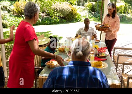 Mother and adult son bringing food to family gathered together at home ...