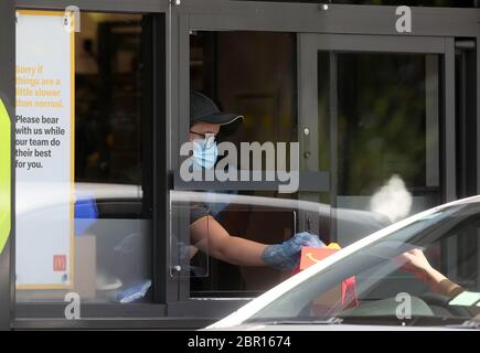 A McDonald's employee serves customers at their drive-thru at the ...