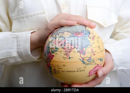 Child holding a small globe in hand on white background Stock Photo - Alamy