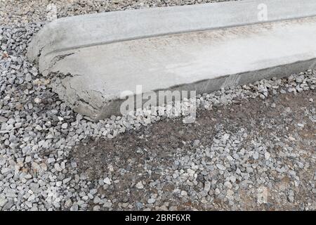 End of a section of rolled, extruded concrete curb alongside a road bed ...