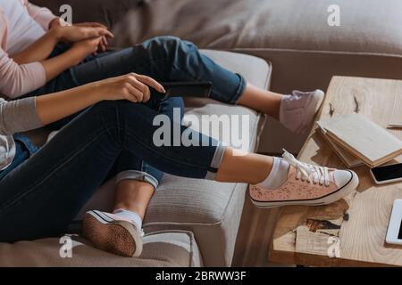 cropped view of girl near gadgets and vegetables holding plastic fork ...