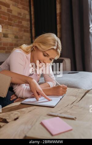 Smiling child pointing at sticky notes on notebook near laptop during ...