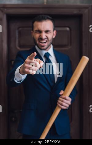 Emotional man with a baseball bat in his hand on a pink background and ...