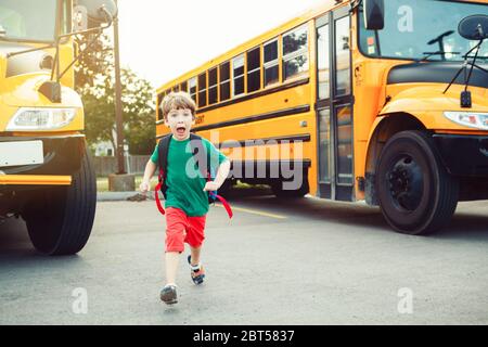 Cute pupil walking to the school bus against dark way in the woods ...