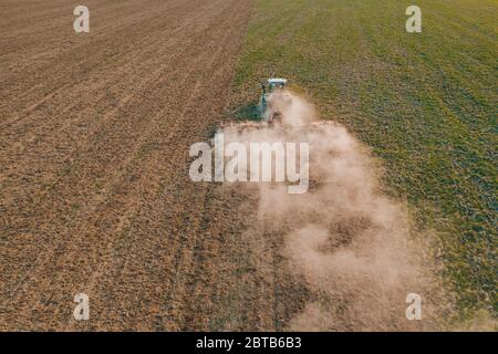 Rear view of a crawler tractor during sowing. Harrowing soil in the ...