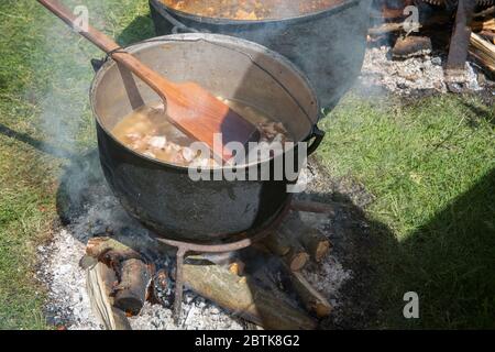 Beef stew in a large pot with vegetables and a wood table, seen from ...