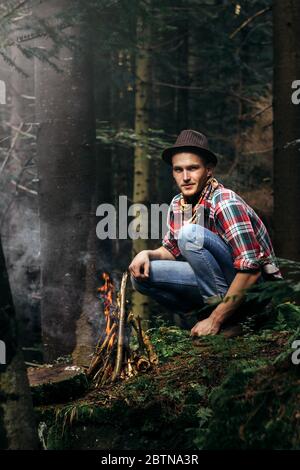 Man starting a fire in the woods using a technique of friction with a ...